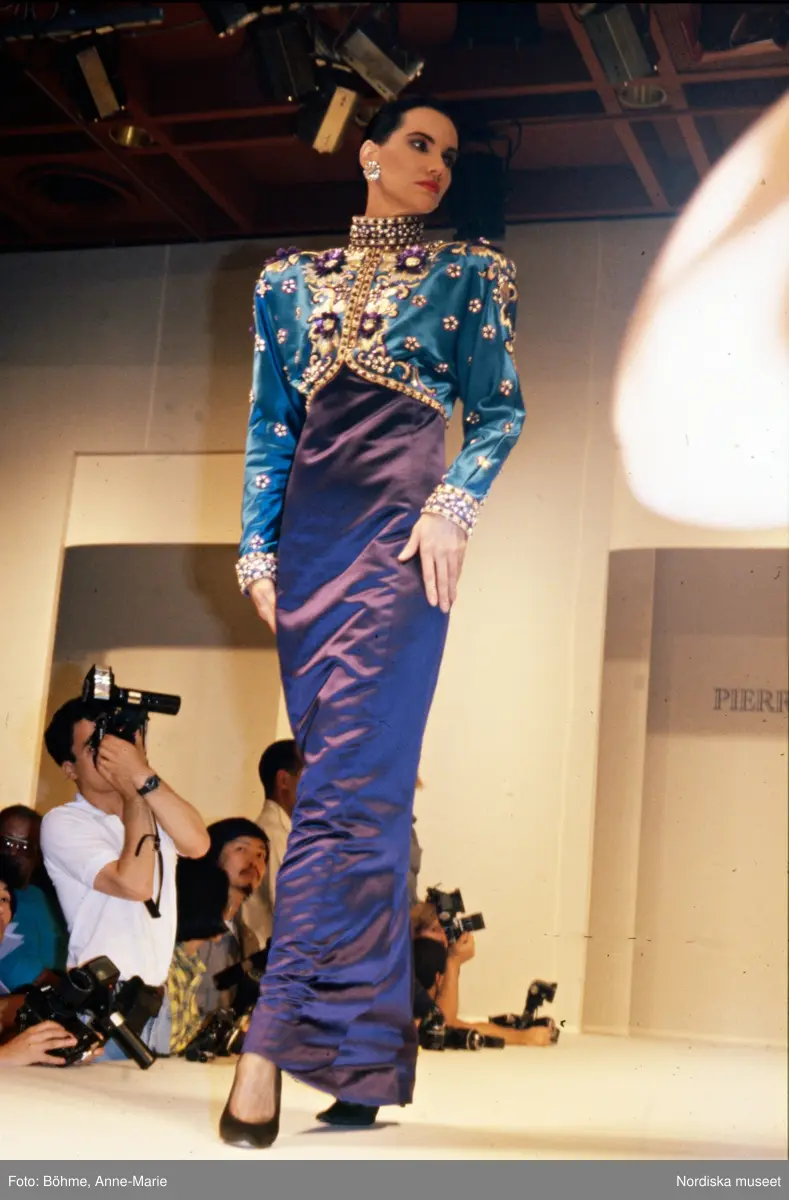 Modevisning. Modell i blålila långklänning och blå sidenjacka med ...