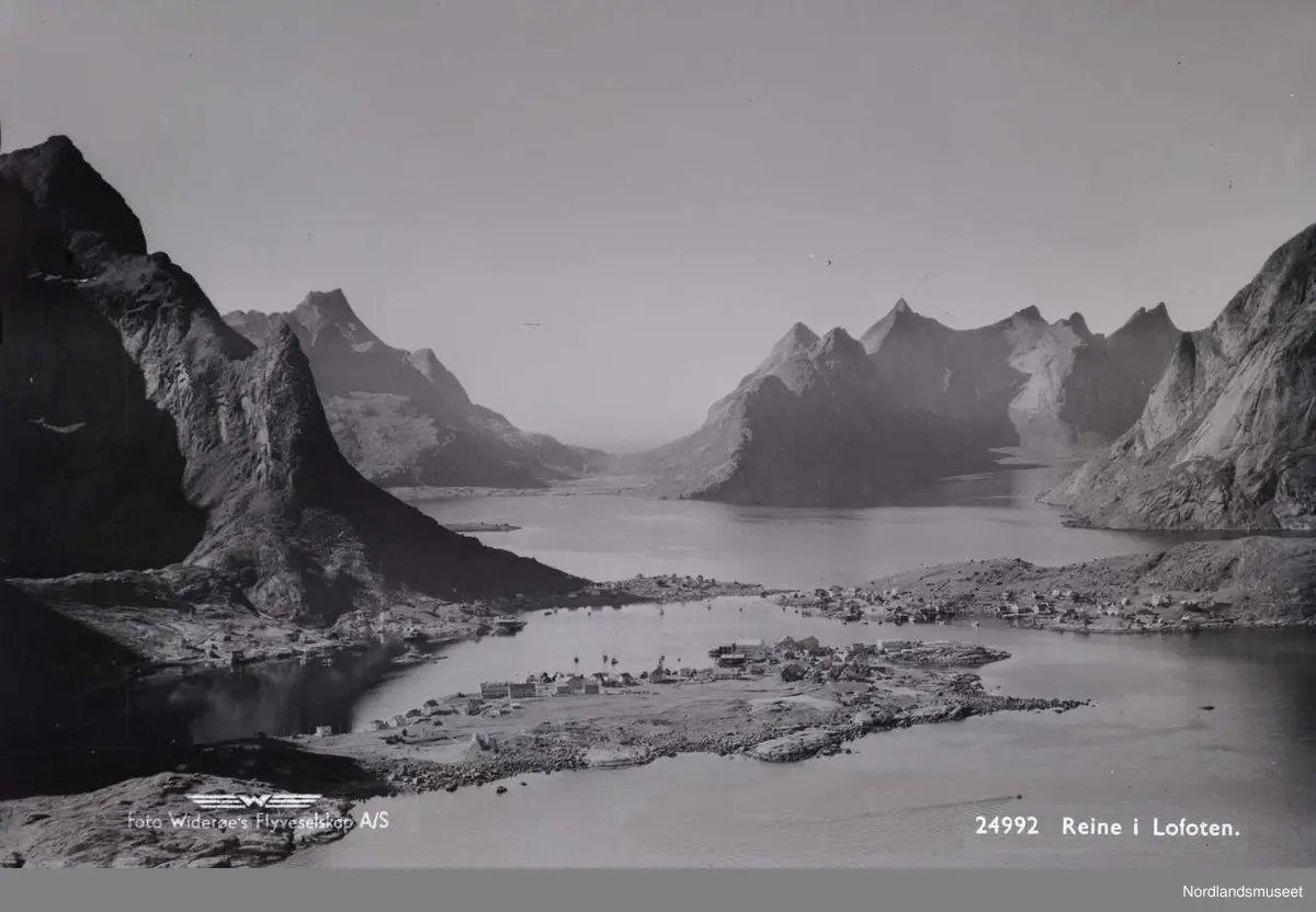 Flyfoto over Reine med omegn. Havna med bygninger, bebyggelse. Havet og ...