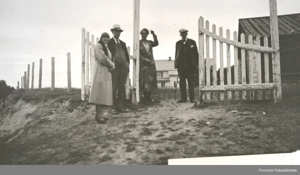 Fire personer ved porten til Saga. Dobbelport med hvite stakitter av ...