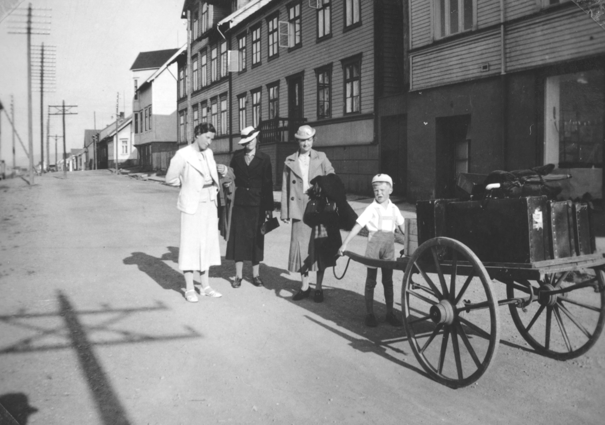 Tor Hauge står og holder skjekene på ei handvogn, med store hjul ...