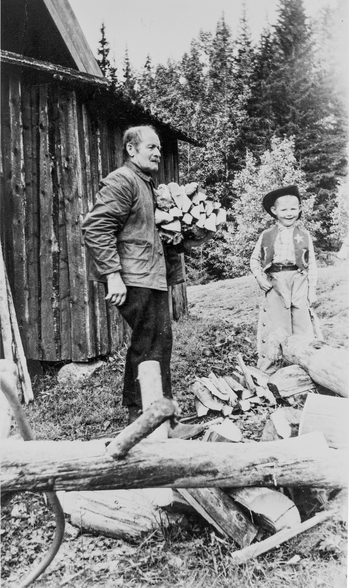 Mann ved fyringsved, gjort klart på gamlemåten med sagkrakk og øks. Til ...