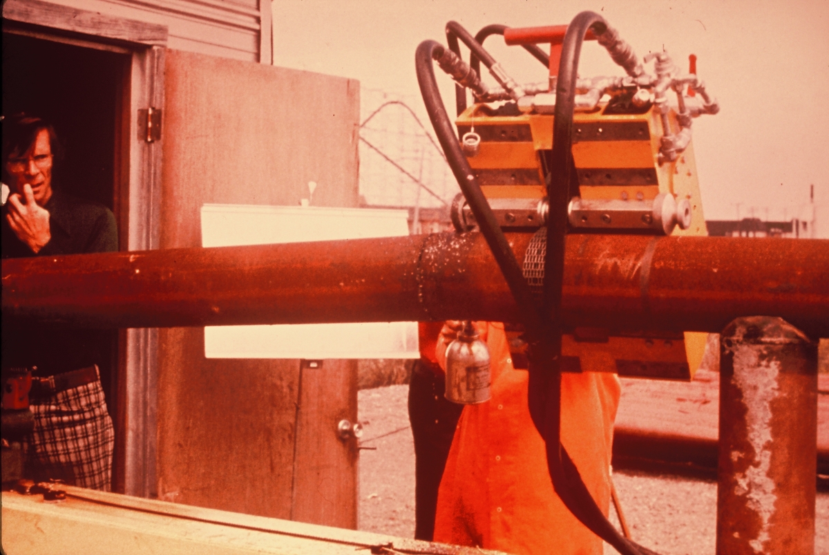 En mann arbeider med reparasjon av et brukket rør. En maskin er festet ...