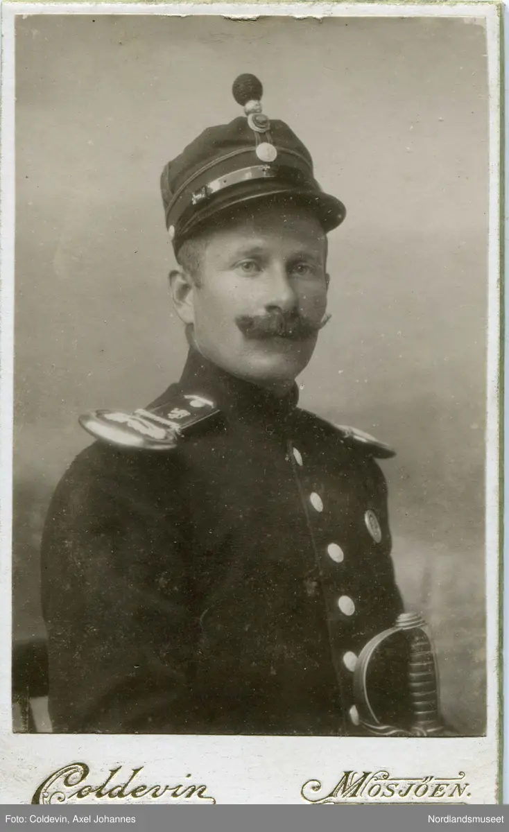 Studioportrett av en mann med bart i uniform. Sittende på en stol ...