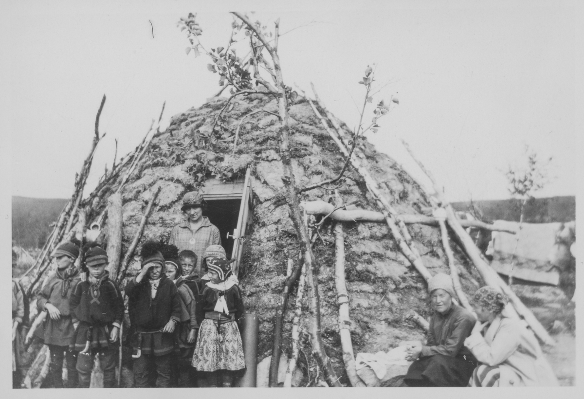 Barn og voksne utenfor en gamme. Ungene har samisk drakt. - Sør-Troms ...