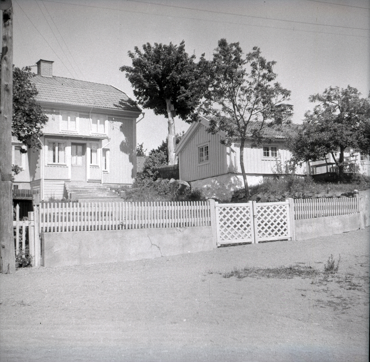 Vy från Figeholm, bostadshus med träpanel och valmat sadeltak. Gata och ...