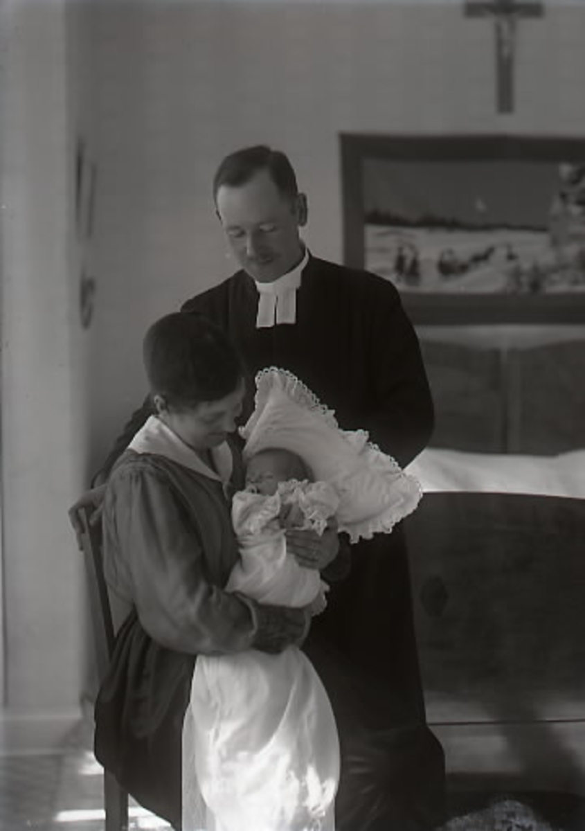 Barndop. Föräldrar och barn där modern sitter med babyn på en stol och ...