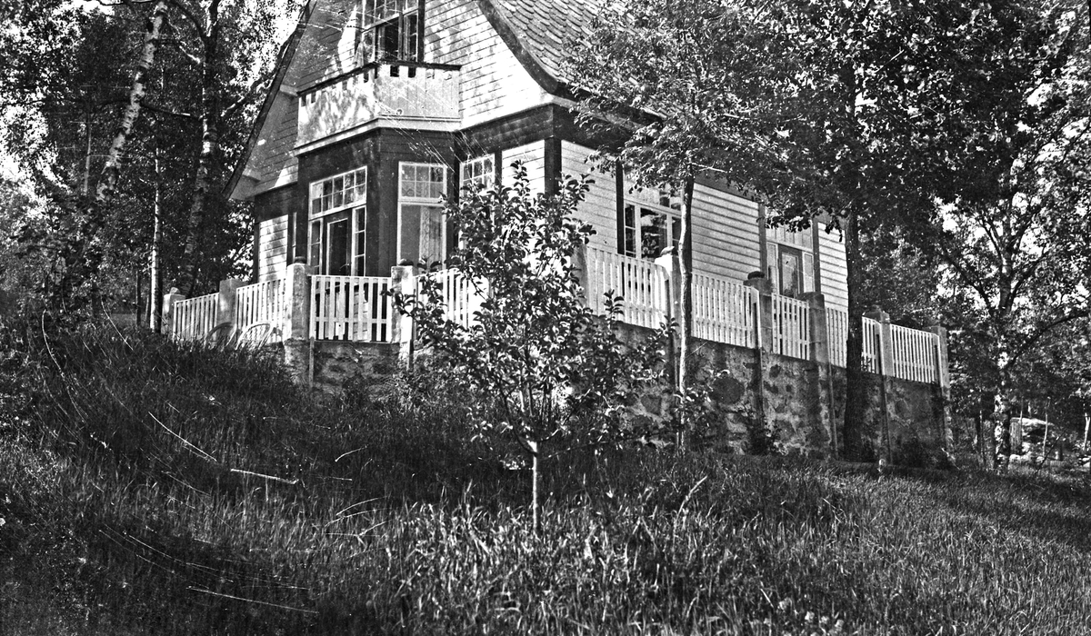 Hus og hage, trær og busker Halvannen etasjes hus med karnapp og altan ...